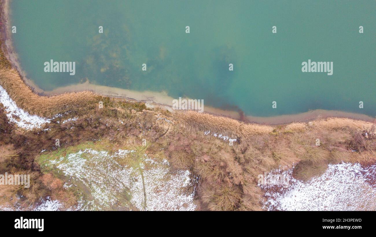 Aerial view of the winter snow covered forest and frozen lake from ...