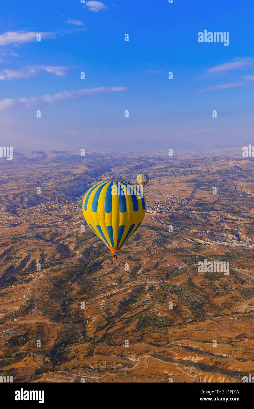 Hot air balloon flying over rocky landscape at sunrise - Cappadocia ...