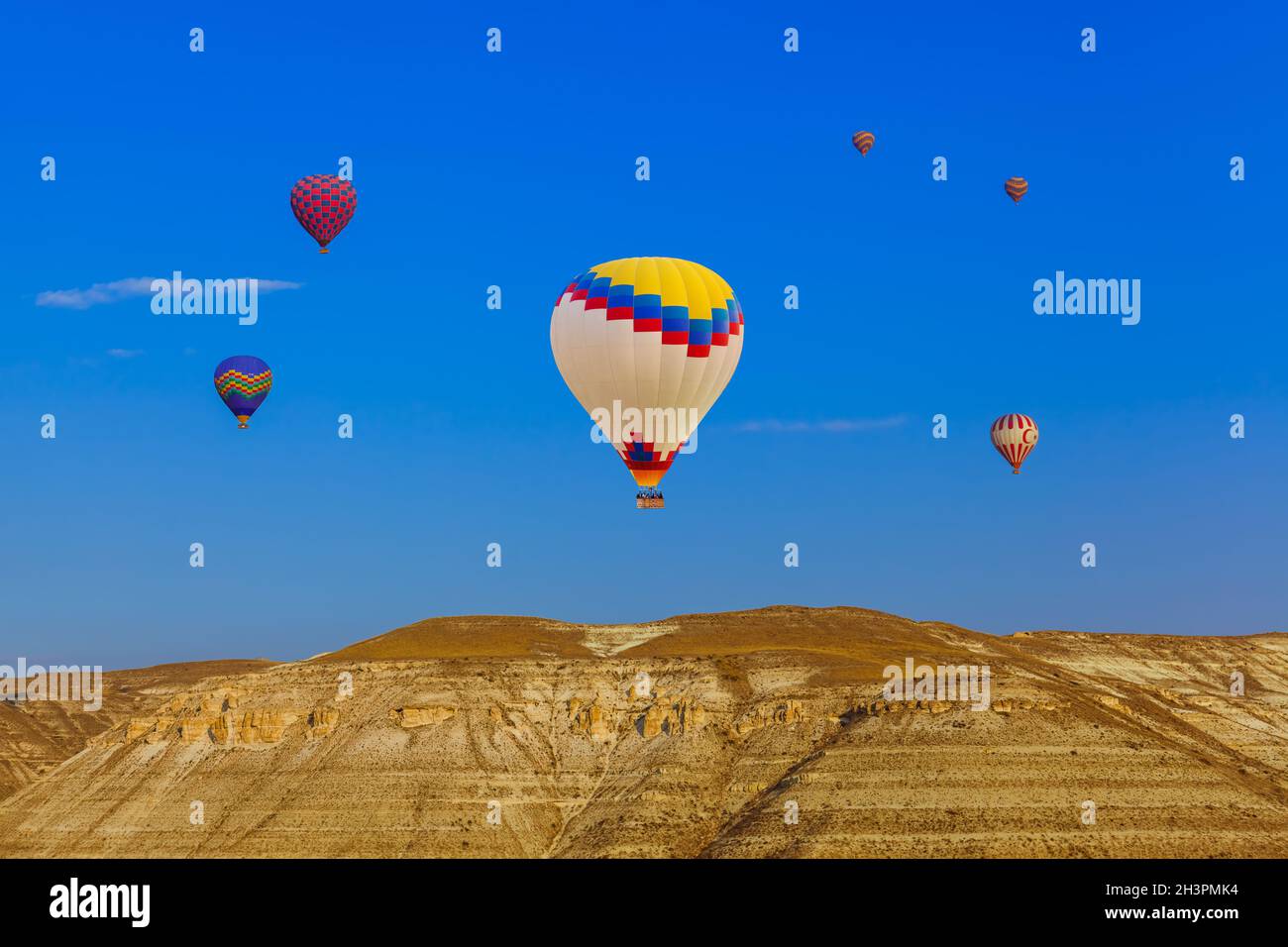 Hot air balloon flying over rocky landscape at sunrise - Cappadocia ...
