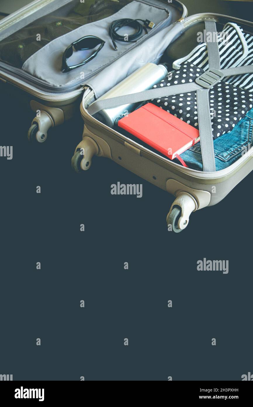 Open suitcase full of clothes isolated on black background Stock Photo ...