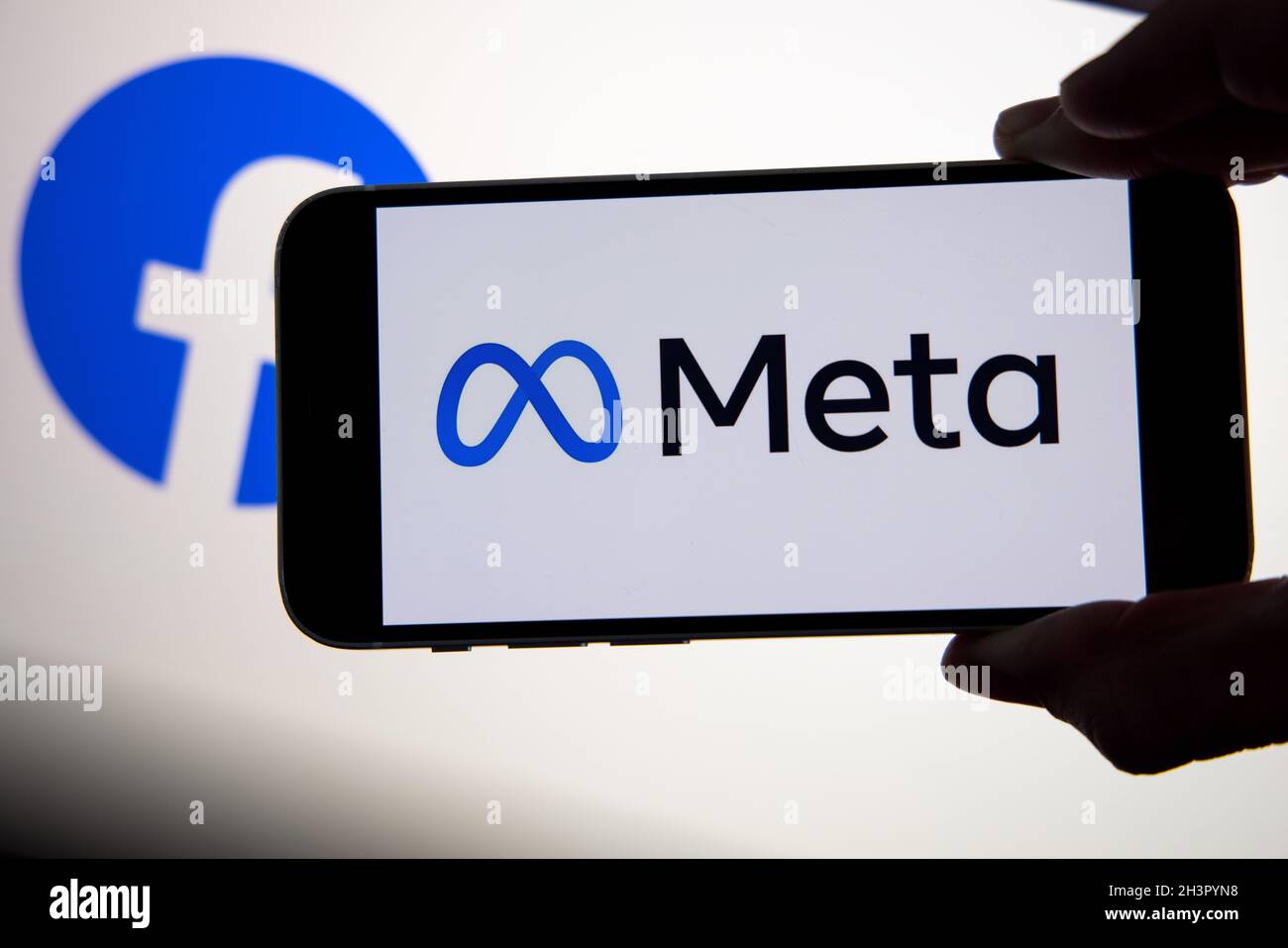 META company logo seen on smartphone in hand with Facebook logo on ...