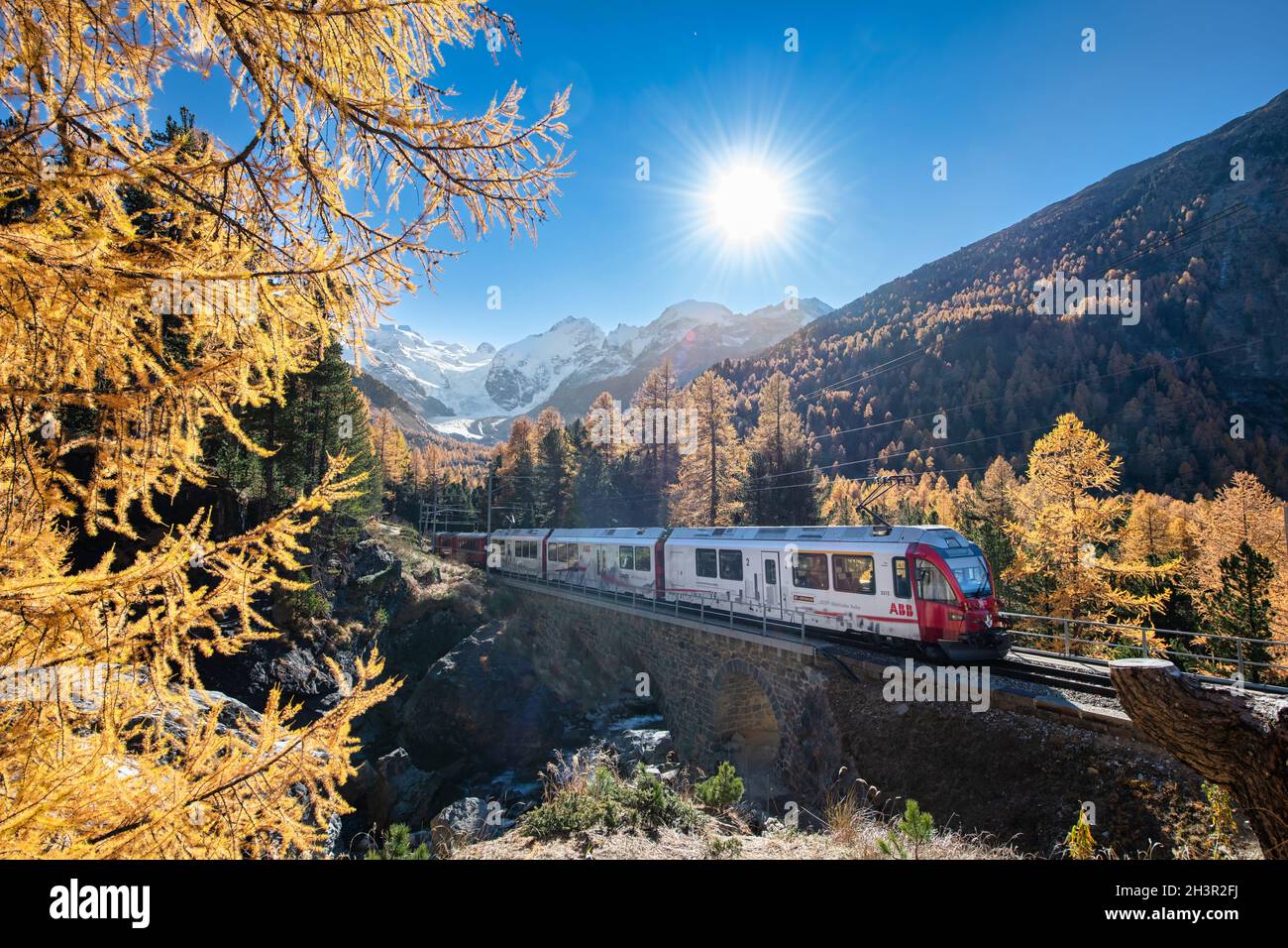 Tourist train on the swiss alps passes through mountains with glaciers ...