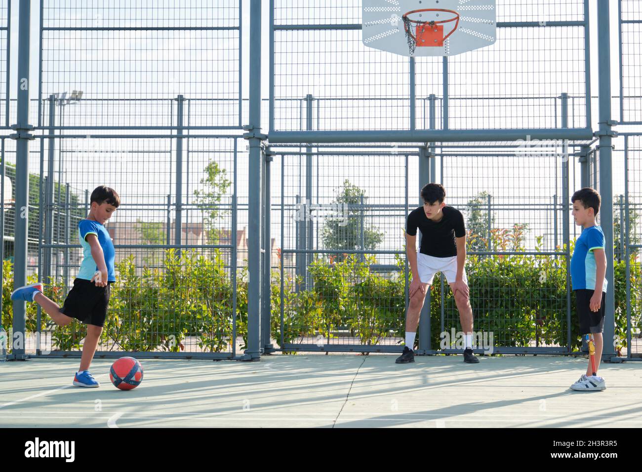 Couch playing football with two students Stock Photo - Alamy
