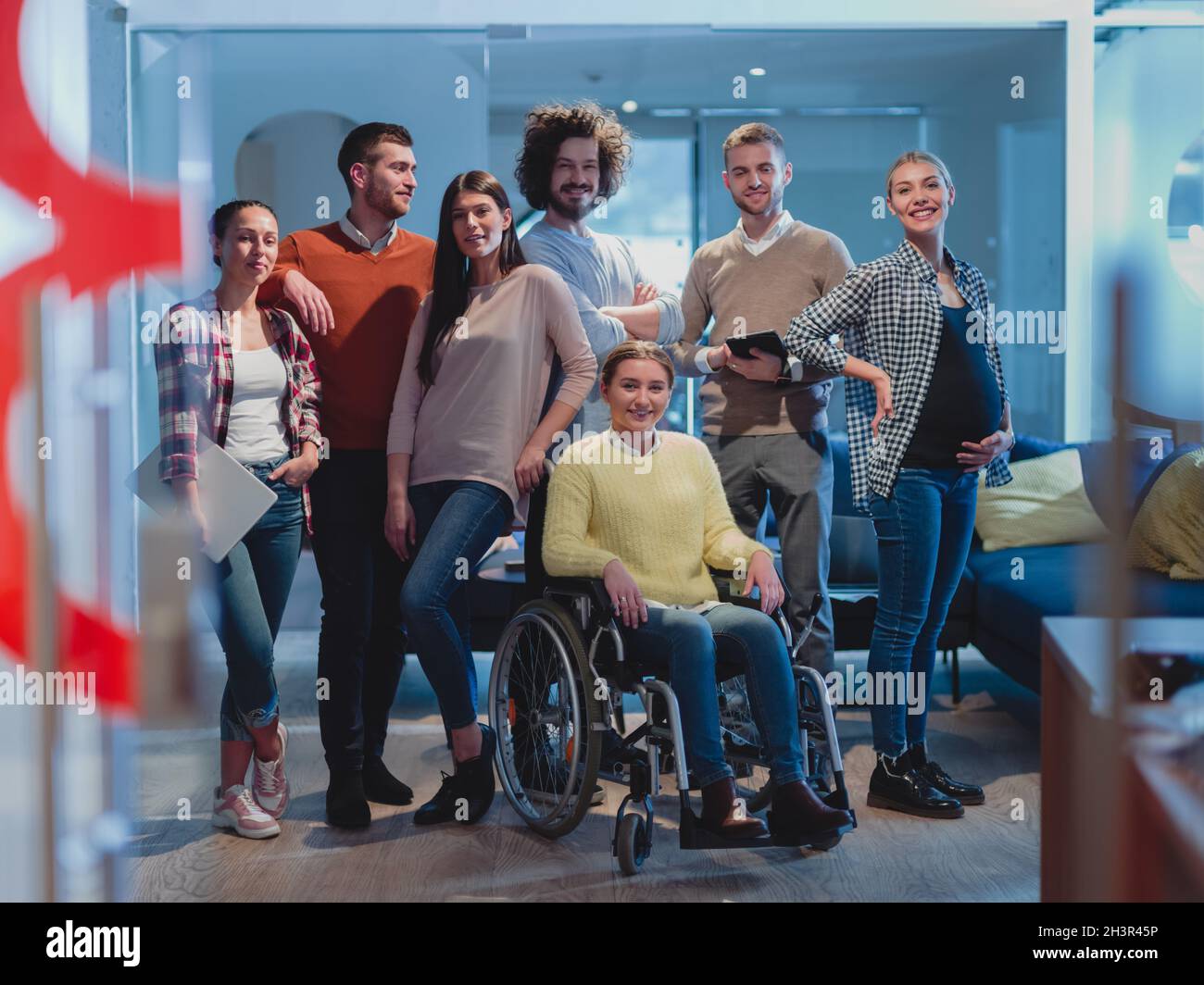 Disabled businesswoman in a wheelchair at the office with coworkers ...