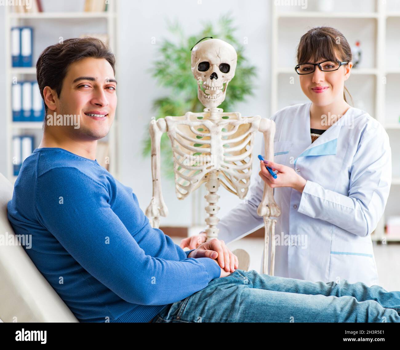 Doctor showing type of injury on skeleton to patient Stock Photo - Alamy