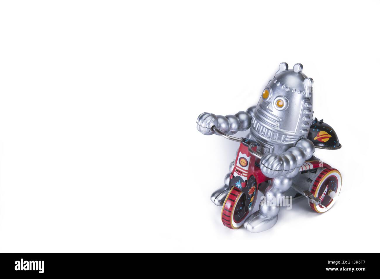 Small retro tin toy robot on tricycle isolated on white background ...