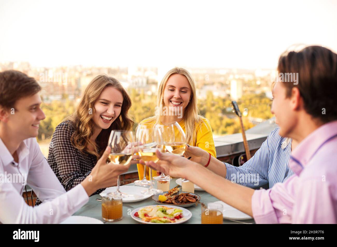 Cheerful friends drinking white wine during roof party Stock Photo - Alamy