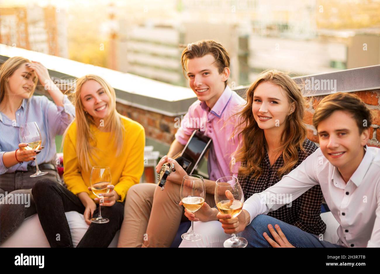 Cheerful friends drinking white wine during roof party Stock Photo - Alamy