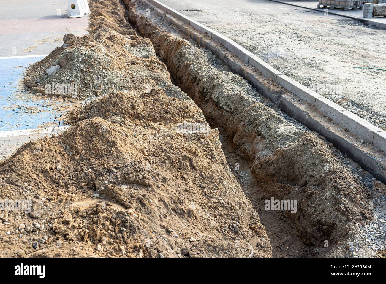 A narrow trench dug along the street on the sidewalk to repair the ...