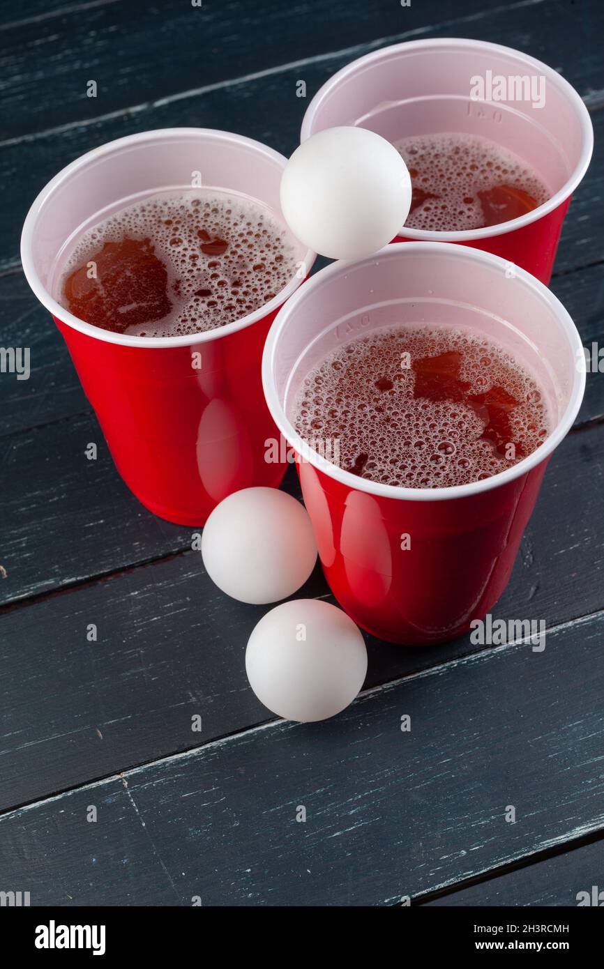 Wooden table with red cups and ball for beer pong Stock Photo - Alamy