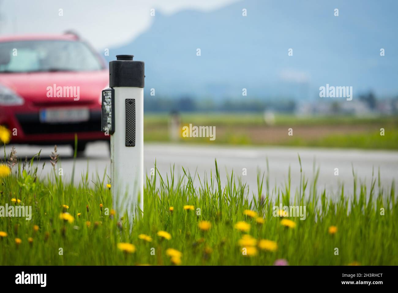 Road in the summer: reflector post, cars, flowers and green grass Stock ...