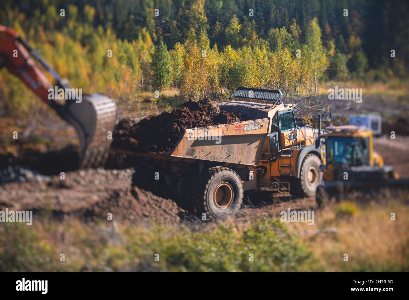 Yellow heavy excavator and dump tip truck tipper excavating sand and ...