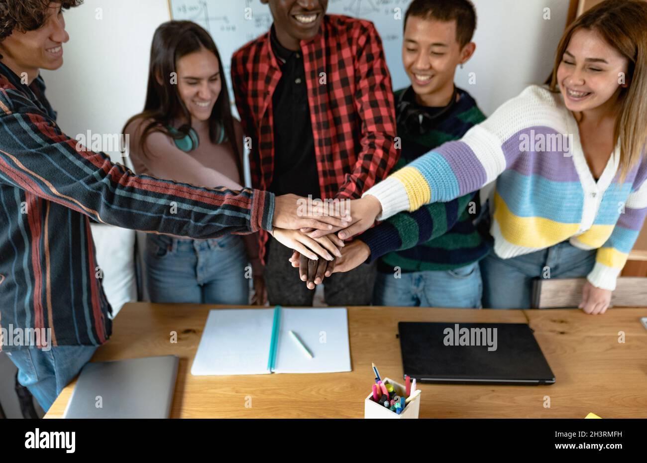 Young multiracial team of students putting their hands together while ...
