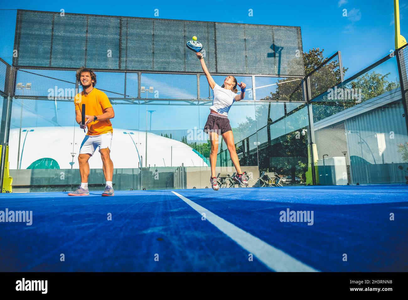 Mixed padel match in a blue grass padel court - Beautiful girl and ...