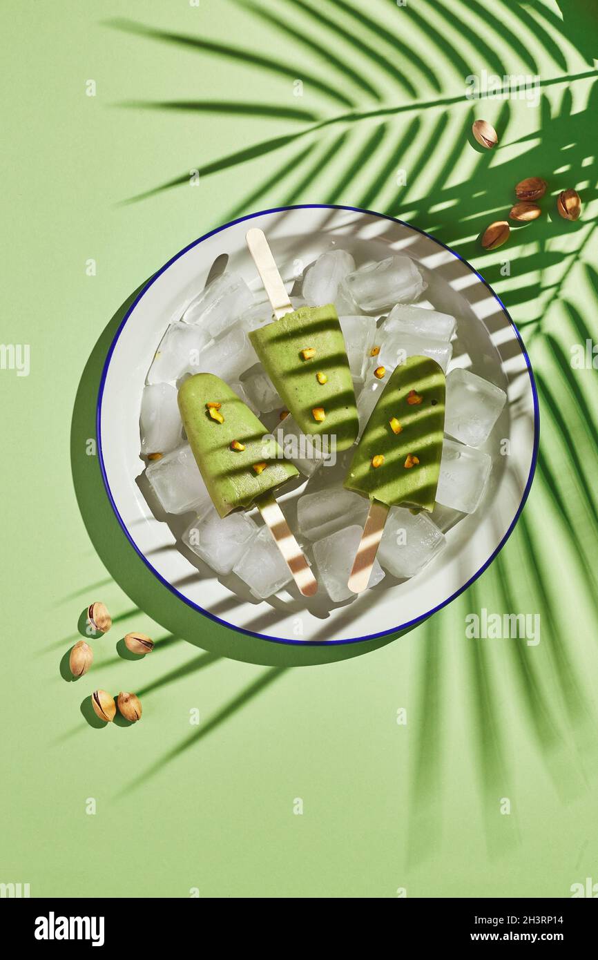 Frozen homemade pistachio popsicle in bowl of ice on green background ...