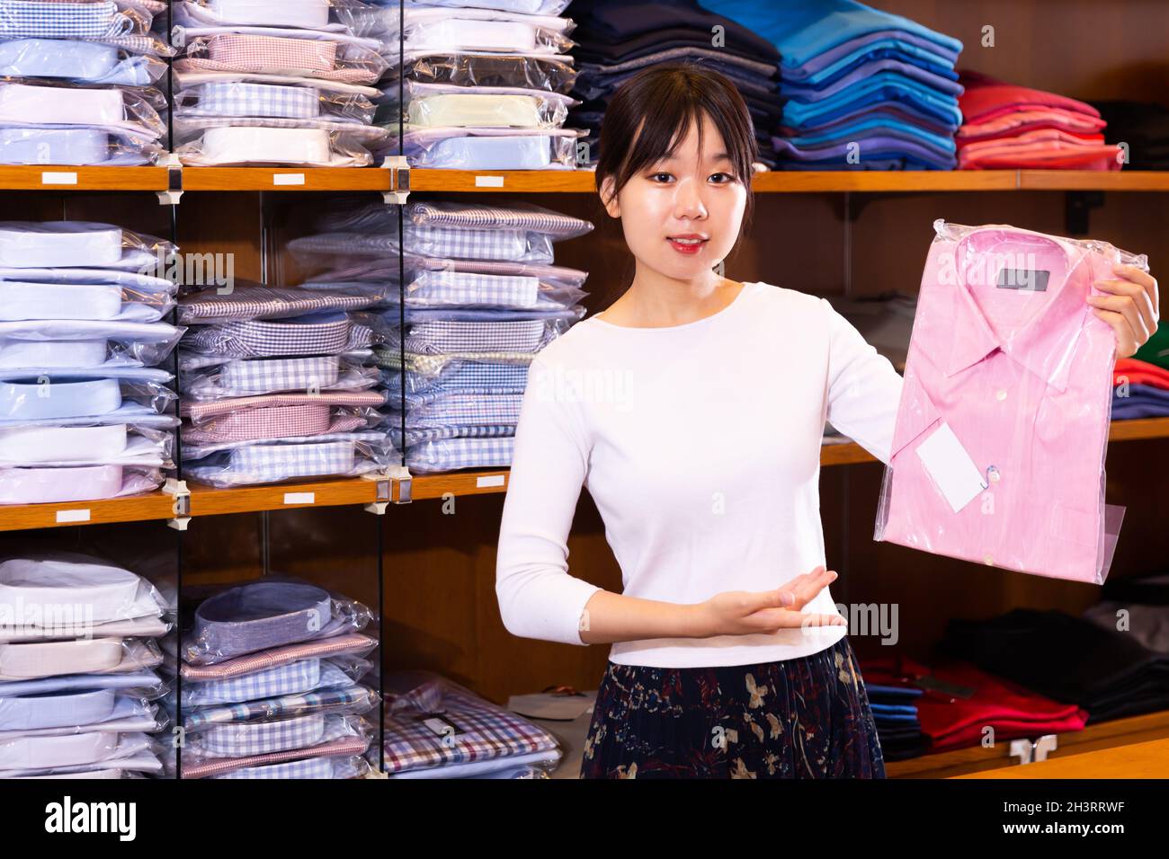 Young Chinese salesgirl offering dress shirt Stock Photo - Alamy