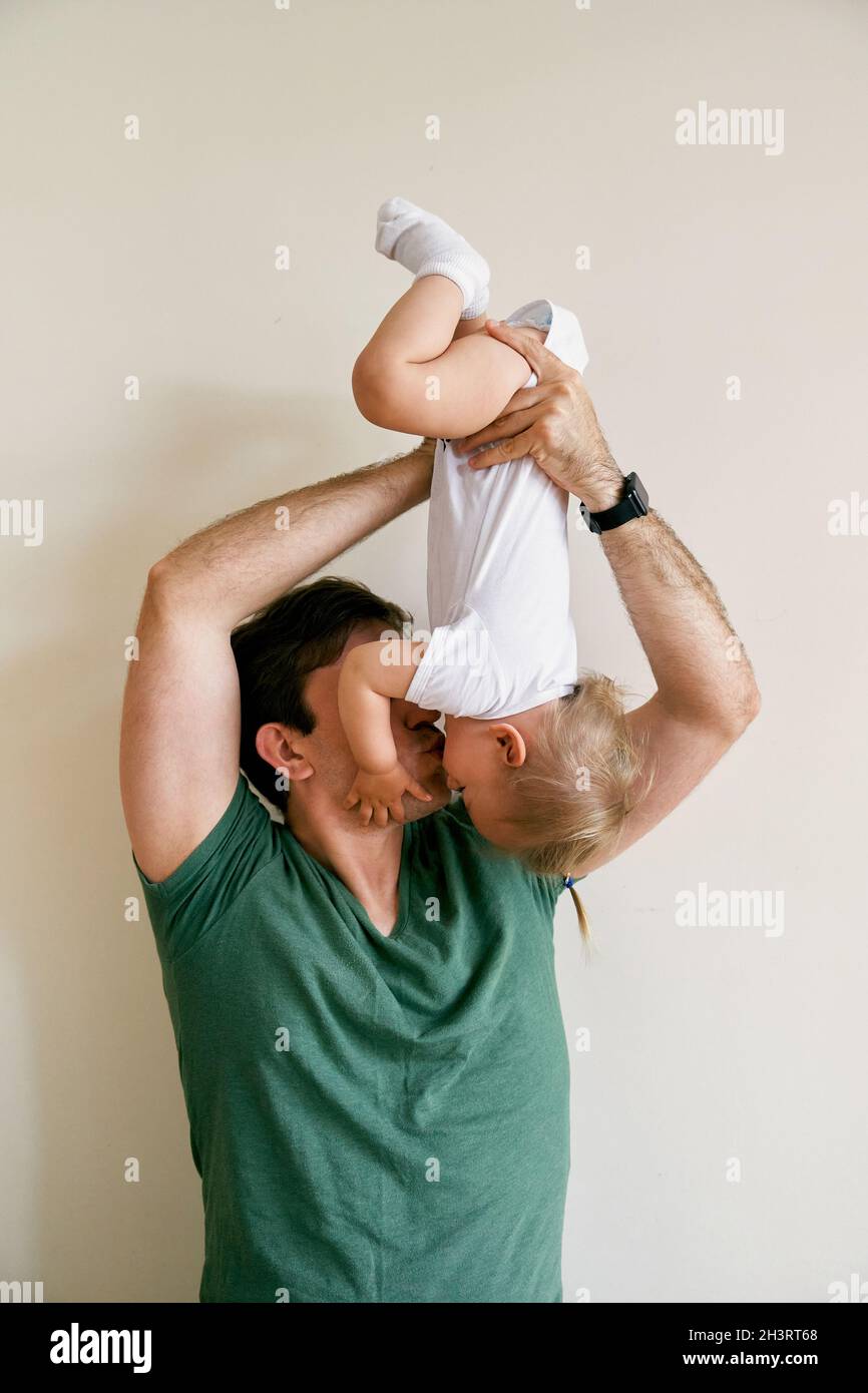 Smiling dad picks up little girl upside down and kiss her Stock Photo ...
