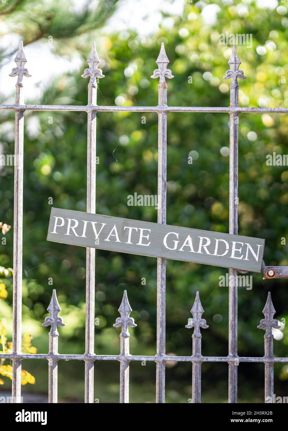 Private garden with metal gate and wooden sign. Keep out message with ...