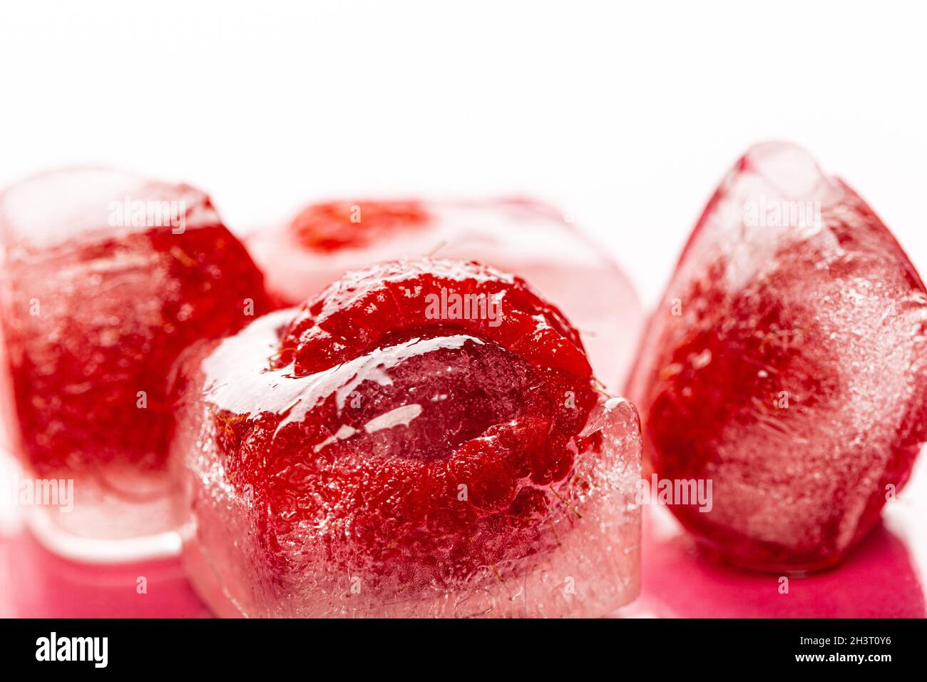 Raspberry ice cubes on pink glossy background Stock Photo - Alamy