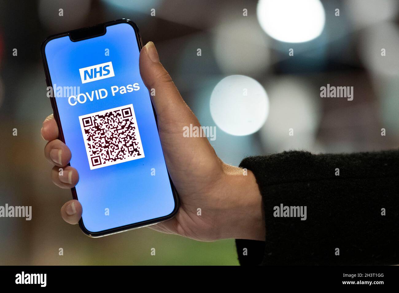 A close-up of a NHS COVID 19 pass in the hands of a woman against a ...
