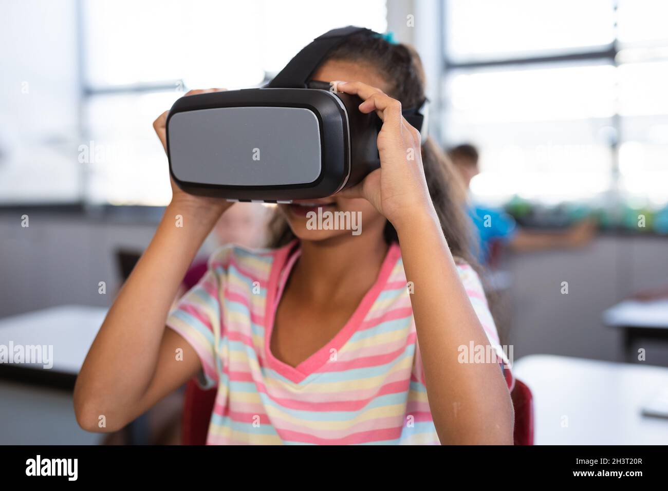 African american girl wearing vr headset while sitting on her desk in ...