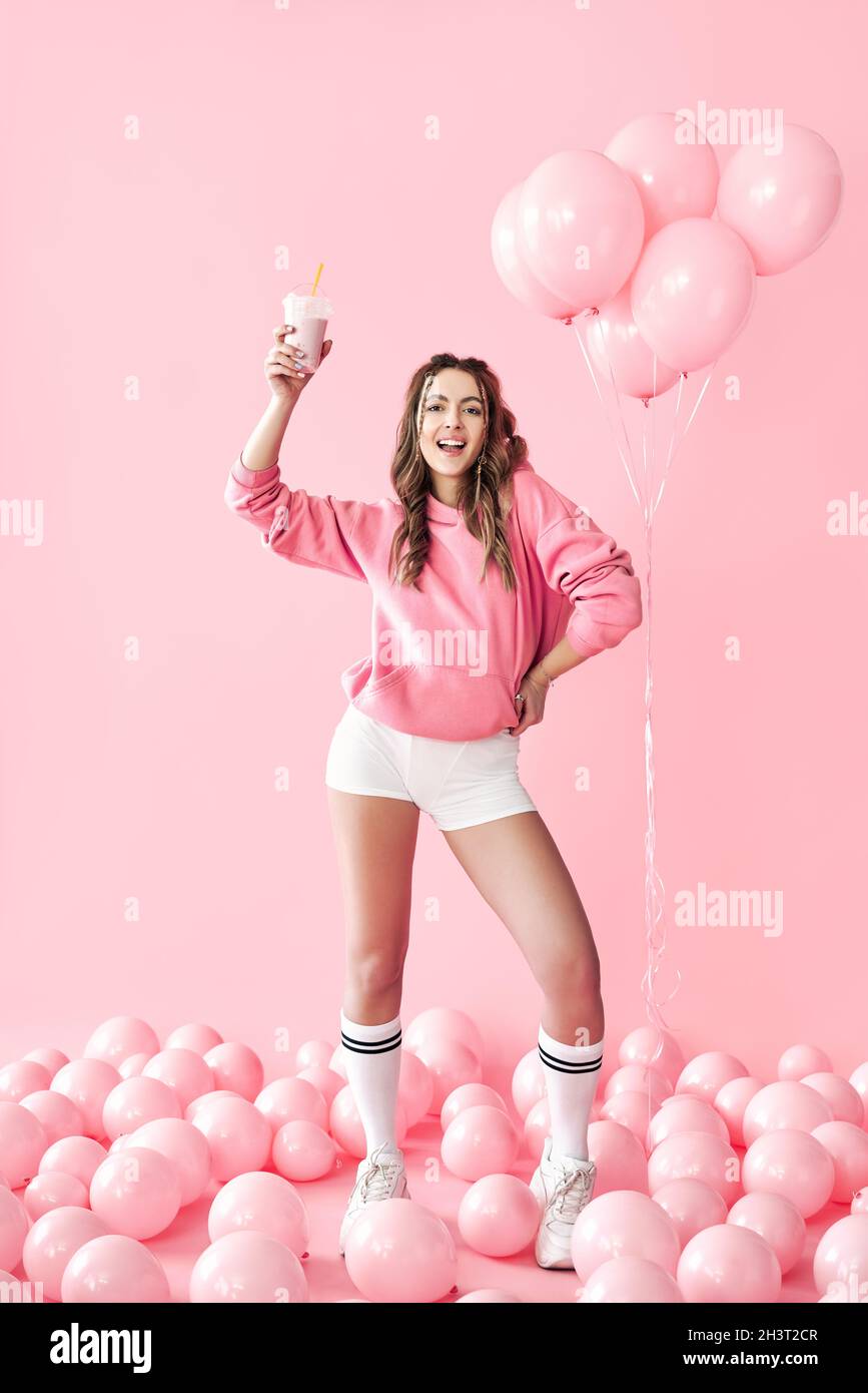 Full length portrait of happy dancing woman with milk shake over pink ...