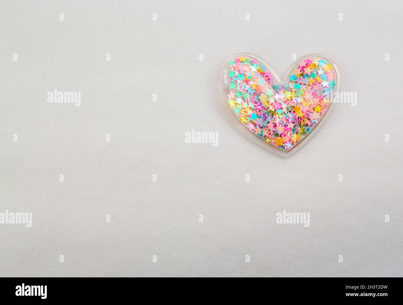 A plastic heart with colorful tiny stars inside isolated on a white ...