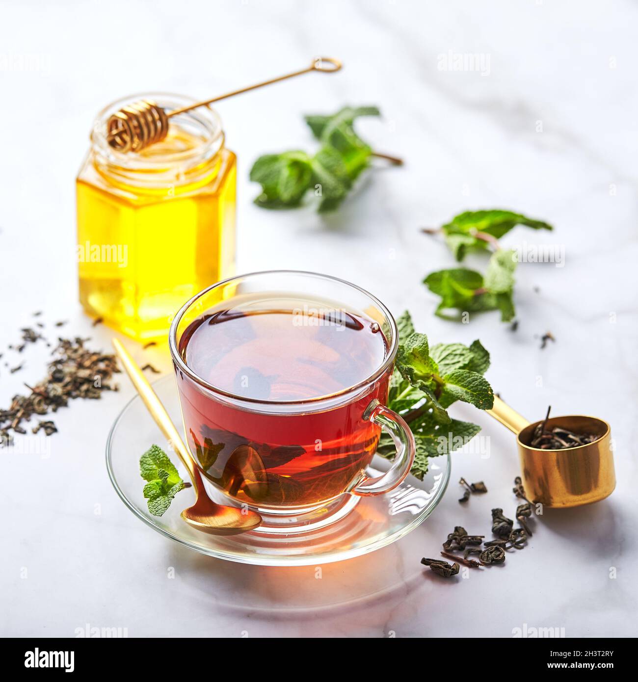 Black tea in glass transparent mug with mint leaves and honey. Calming ...