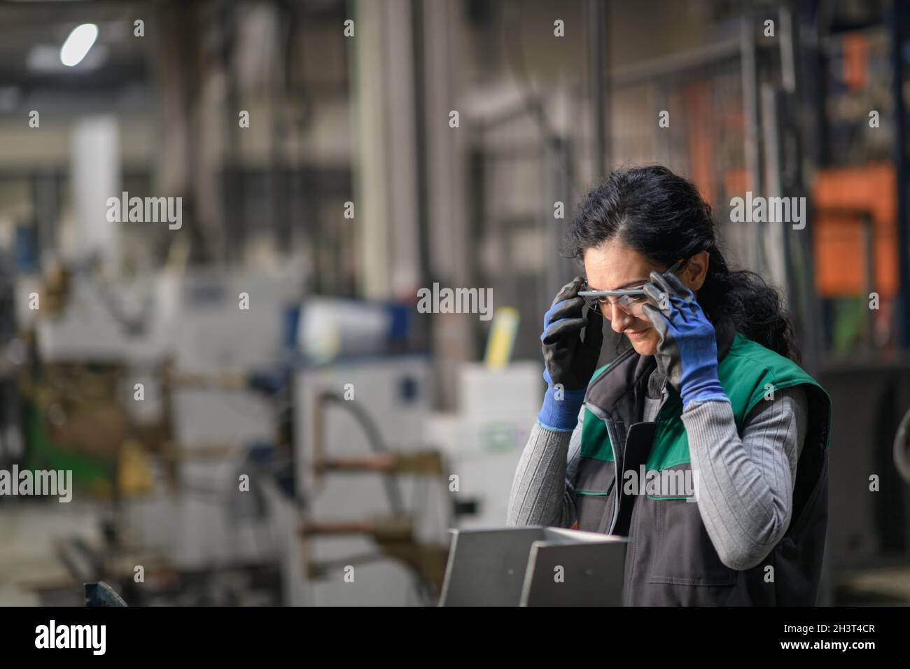 Woman worker wearing safety goggles control lathe machine to drill ...