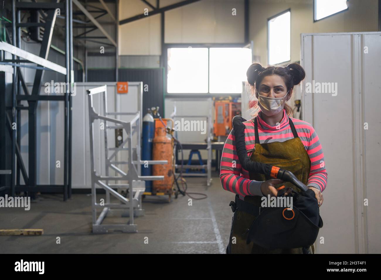 A portrait of a women welder holding a helmet and preparing for a ...