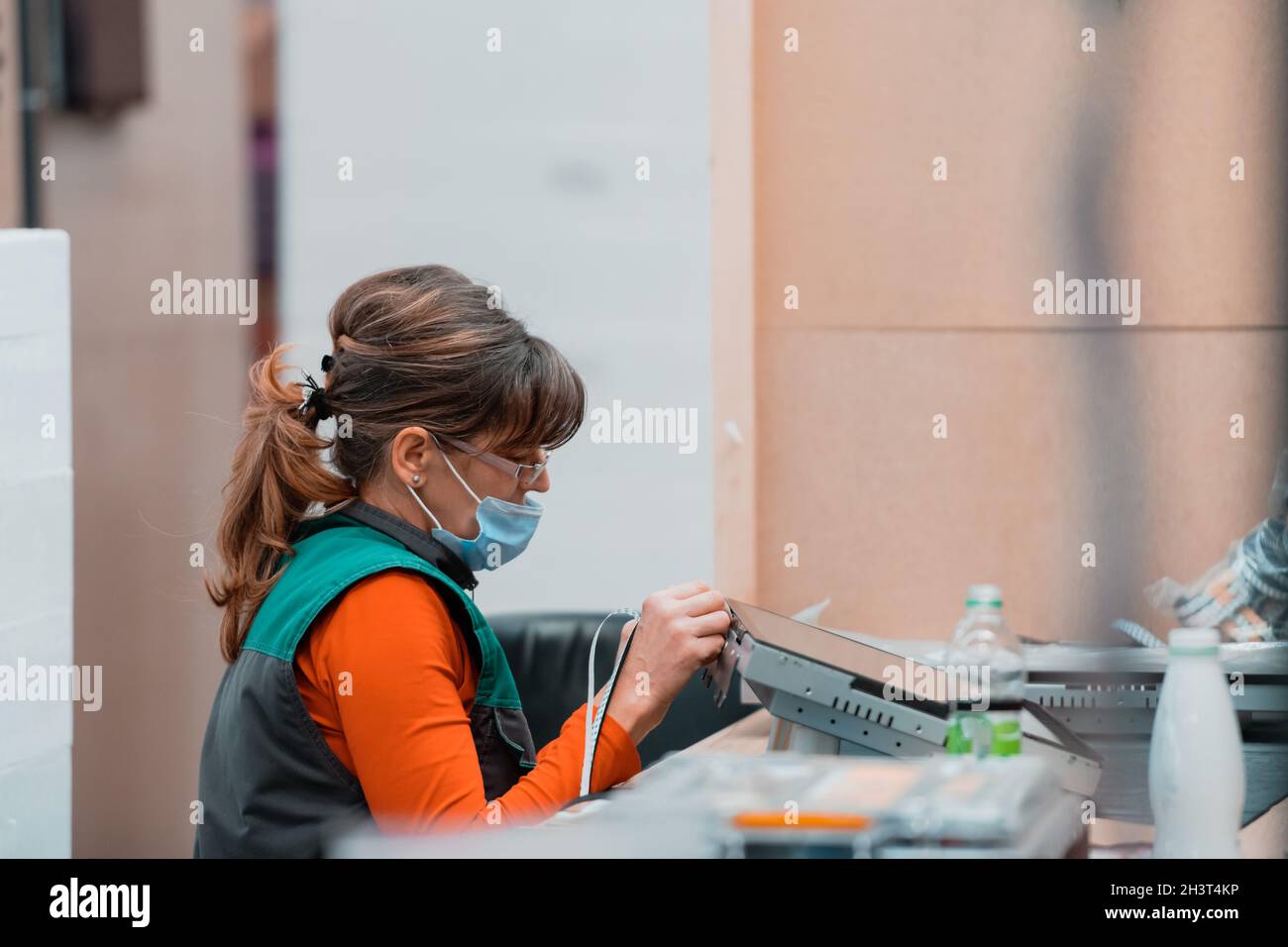 A woman sitting on a chair and assembles a screen for a machine ...
