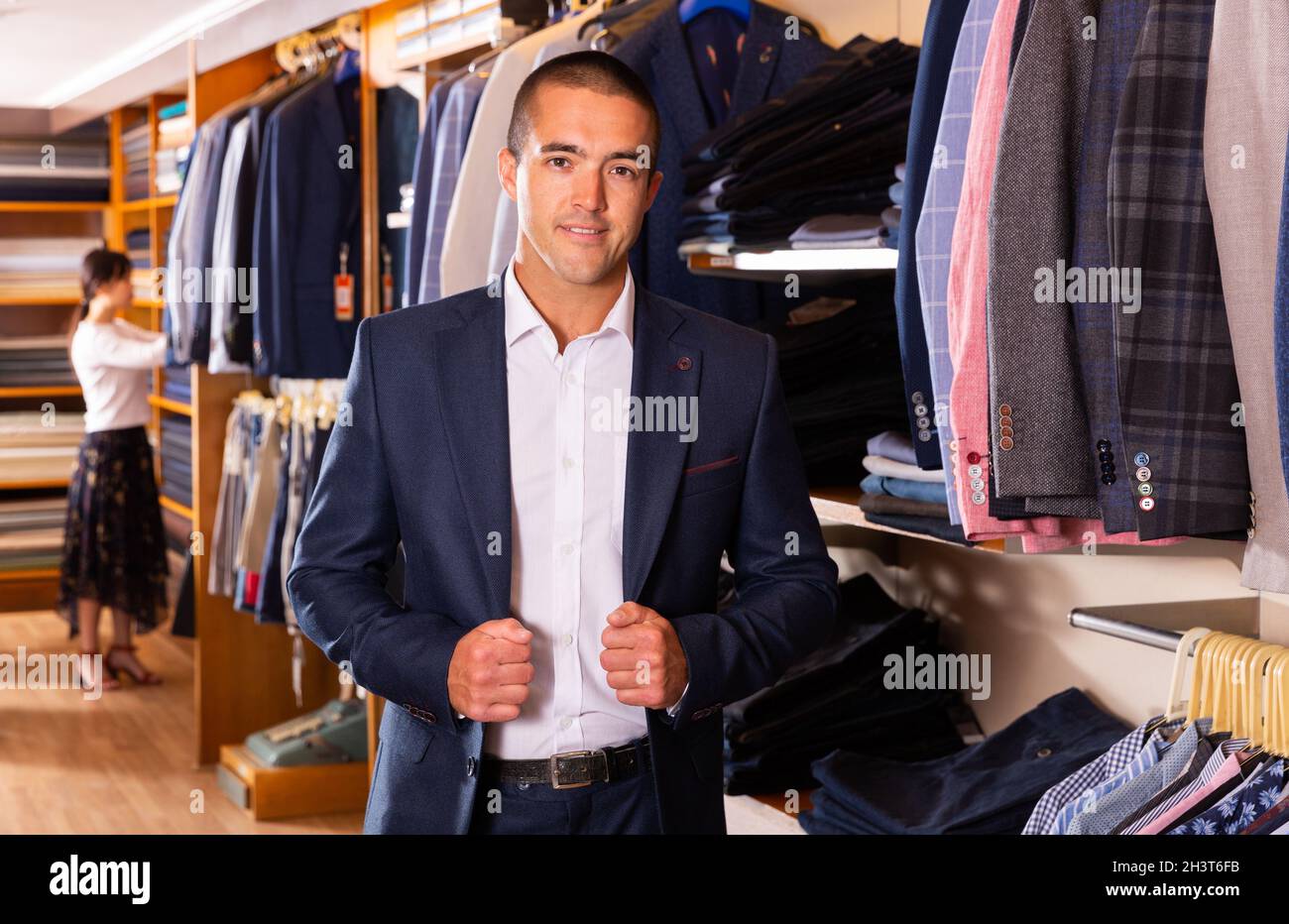 Positive male customer choosing fashion suit in mens store Stock Photo ...