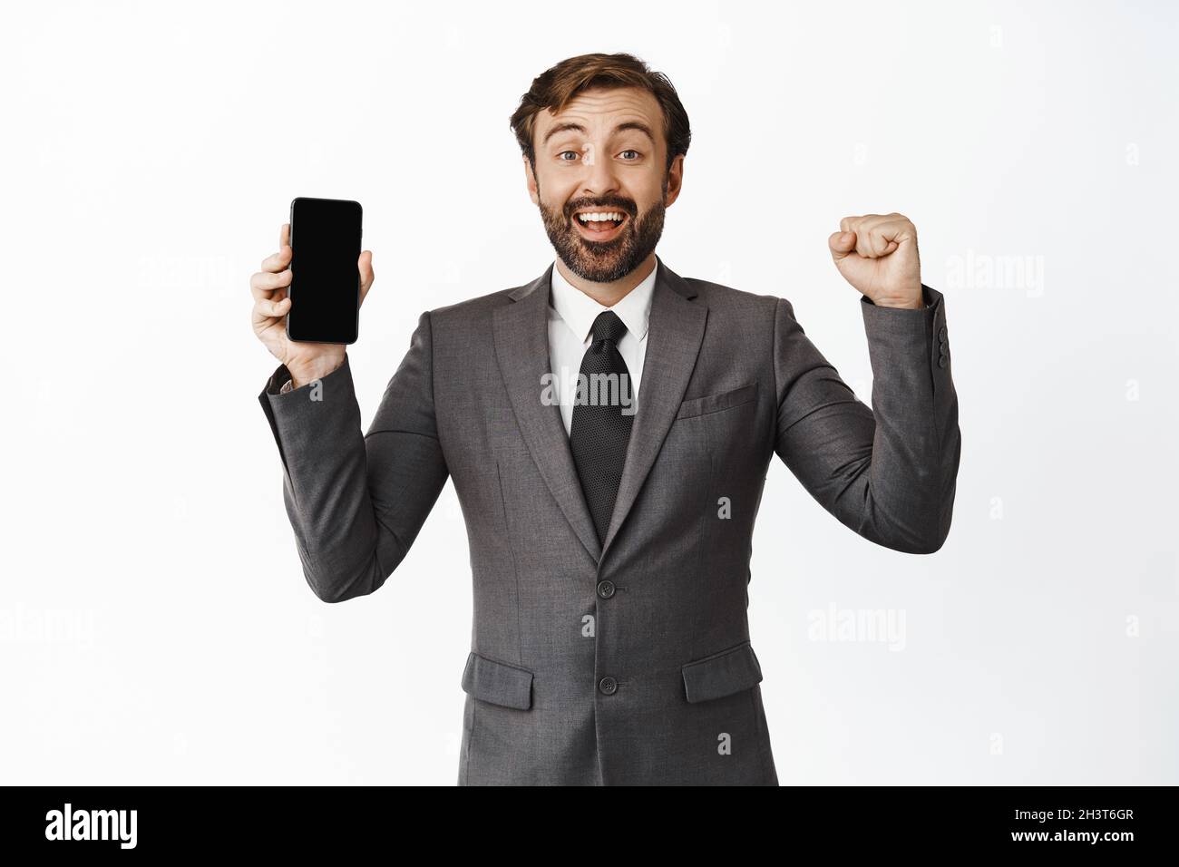 Happy corporate man rejoicing, showing mobile phone screen and jumping ...