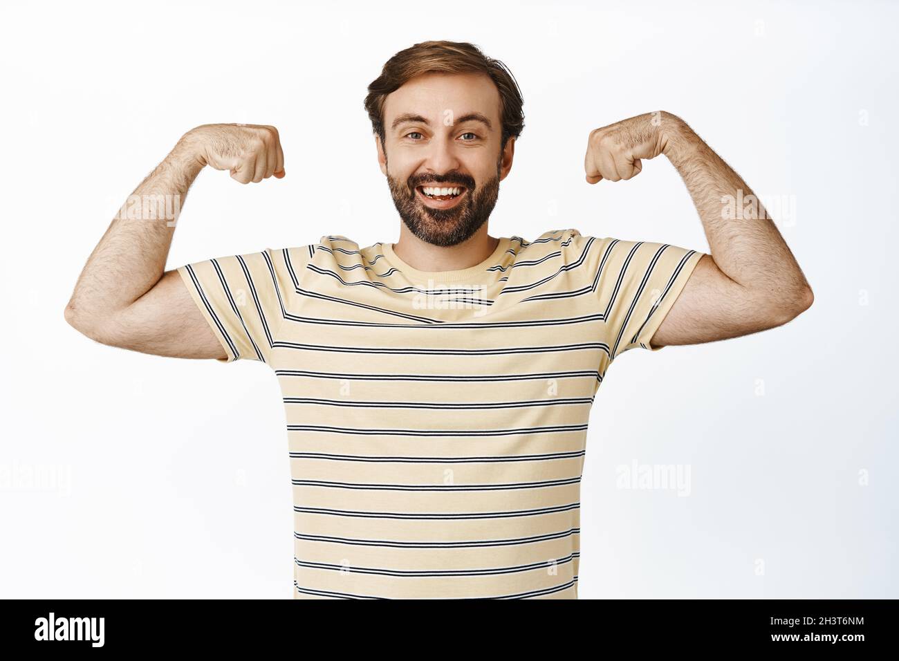 Image of happy bearded guy shows his muscles, flexing biceps on arms ...