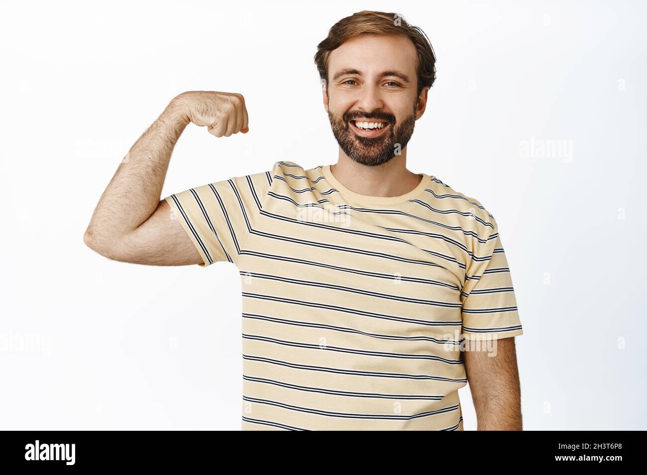 Smiling happy and healthy man showing his muscles, flexing biceps on ...