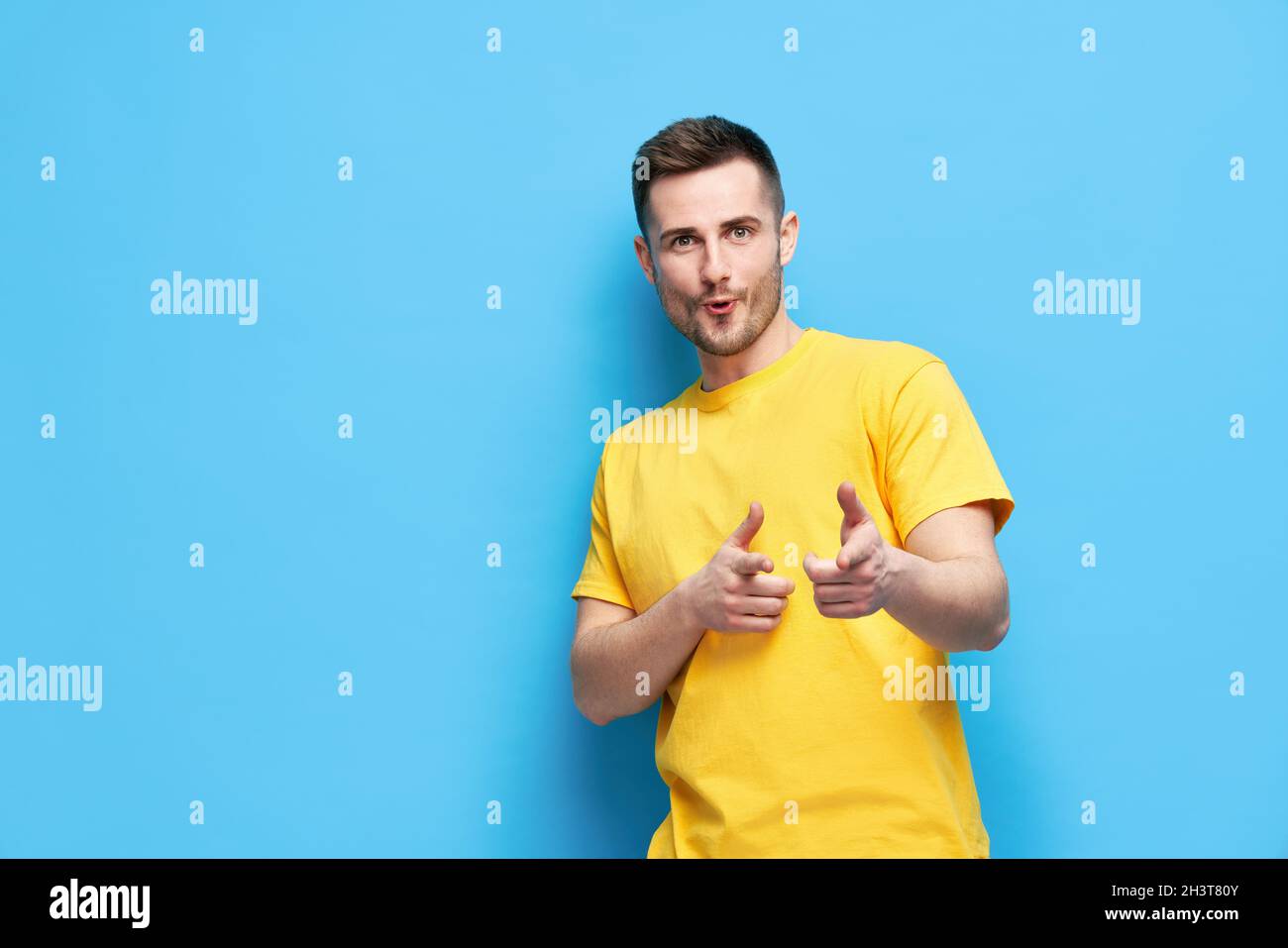 Funny joyful man pointing at you and looking to camera on blue ...
