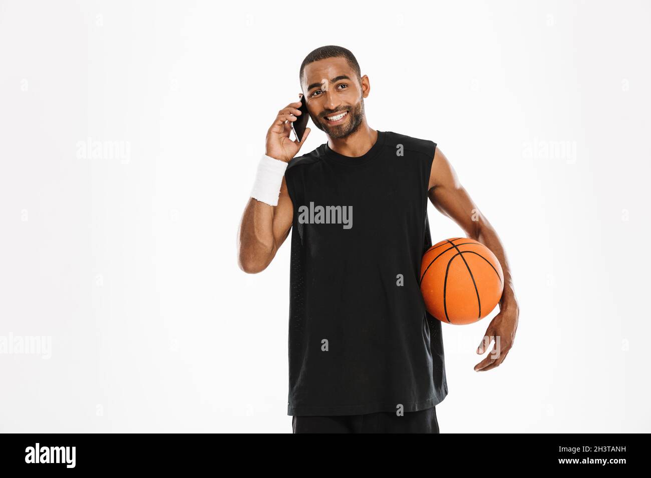 Happy african young basketball player standing talking on mobile phone ...