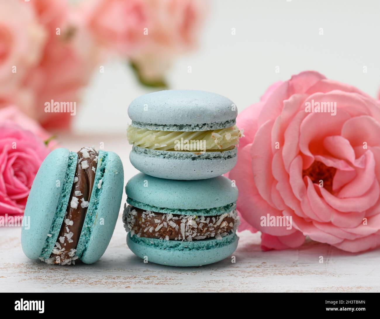 A stack of blue macarons on a white table and pink rosebuds Stock Photo ...