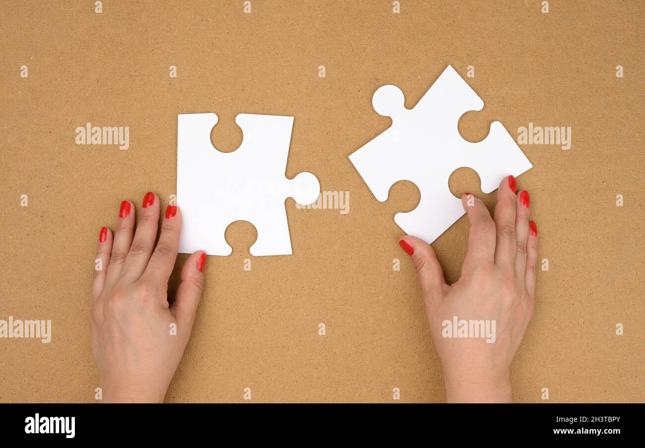 Two empty paper white pieces of puzzles in female hands, puzzle ...