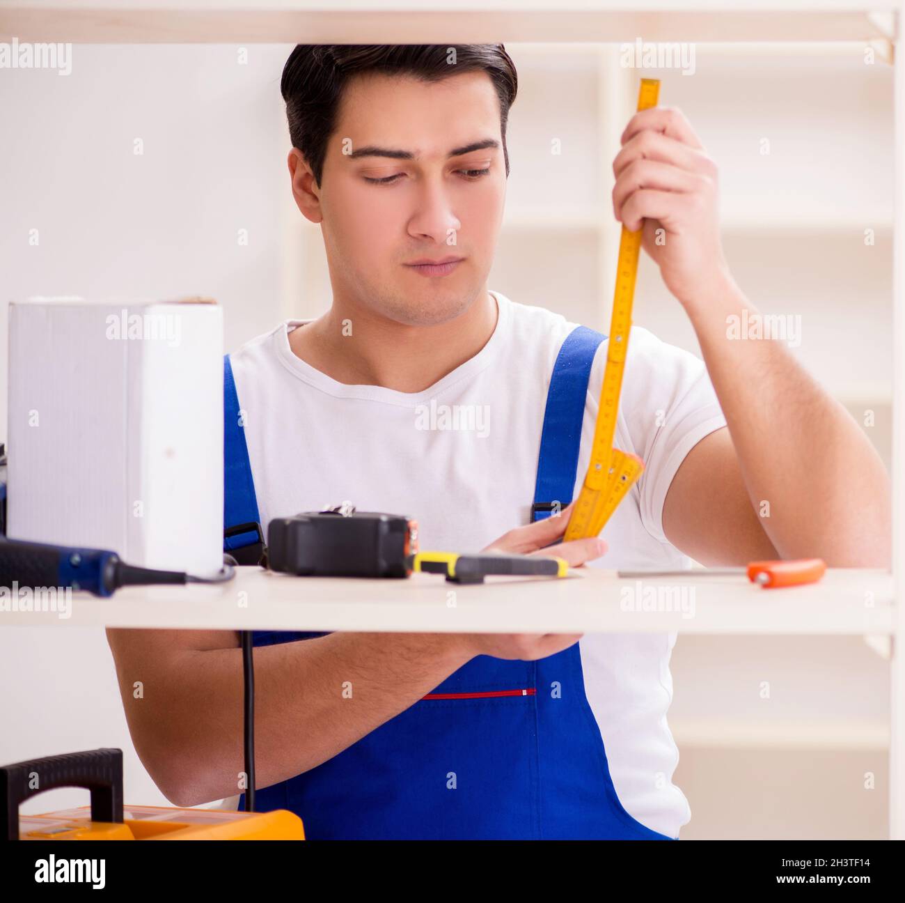 Worker man repairing assembling bookshelf Stock Photo - Alamy