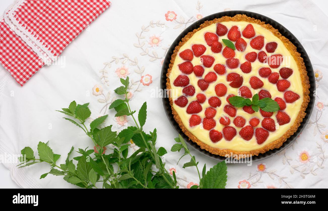 Baked round tart with strawberries and tender milk cream on a white ...
