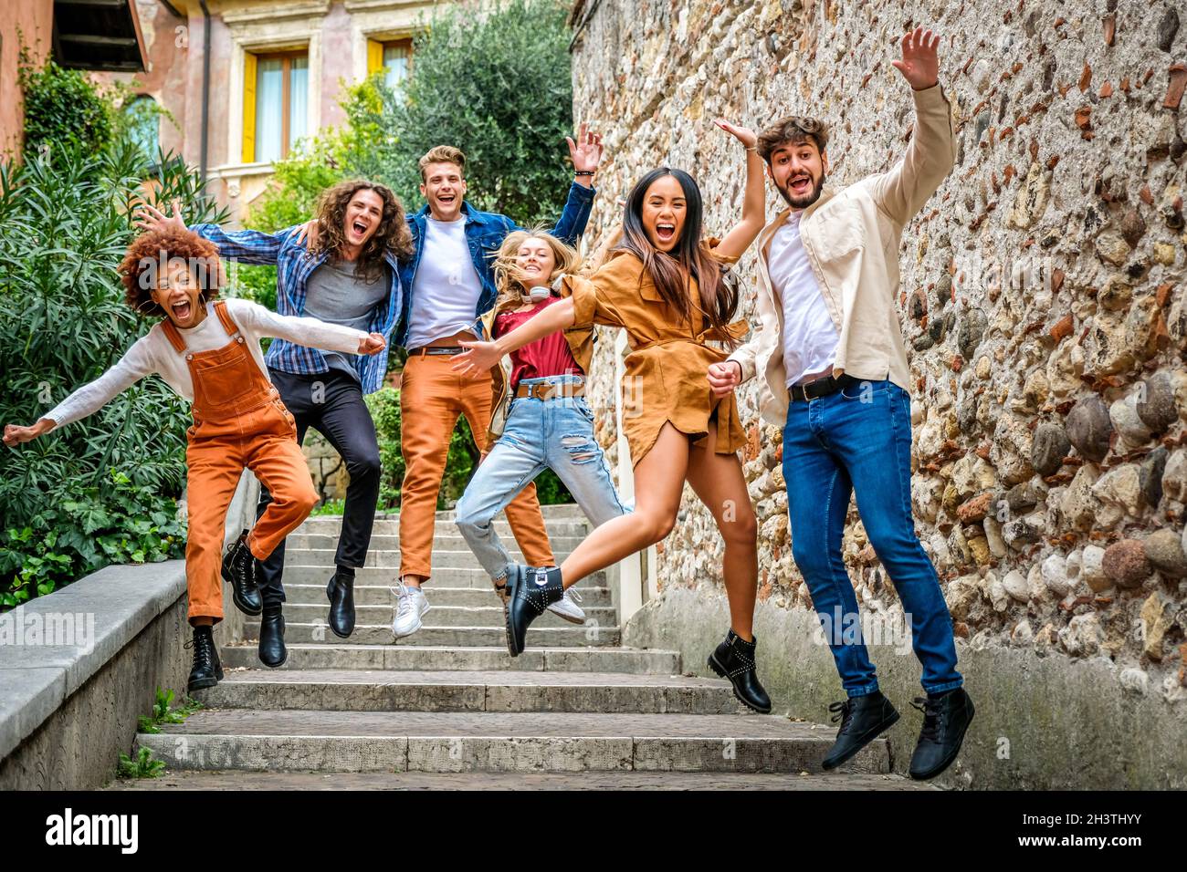 Multi-ethnic group of crazy young people jumping down the stairs in the ...