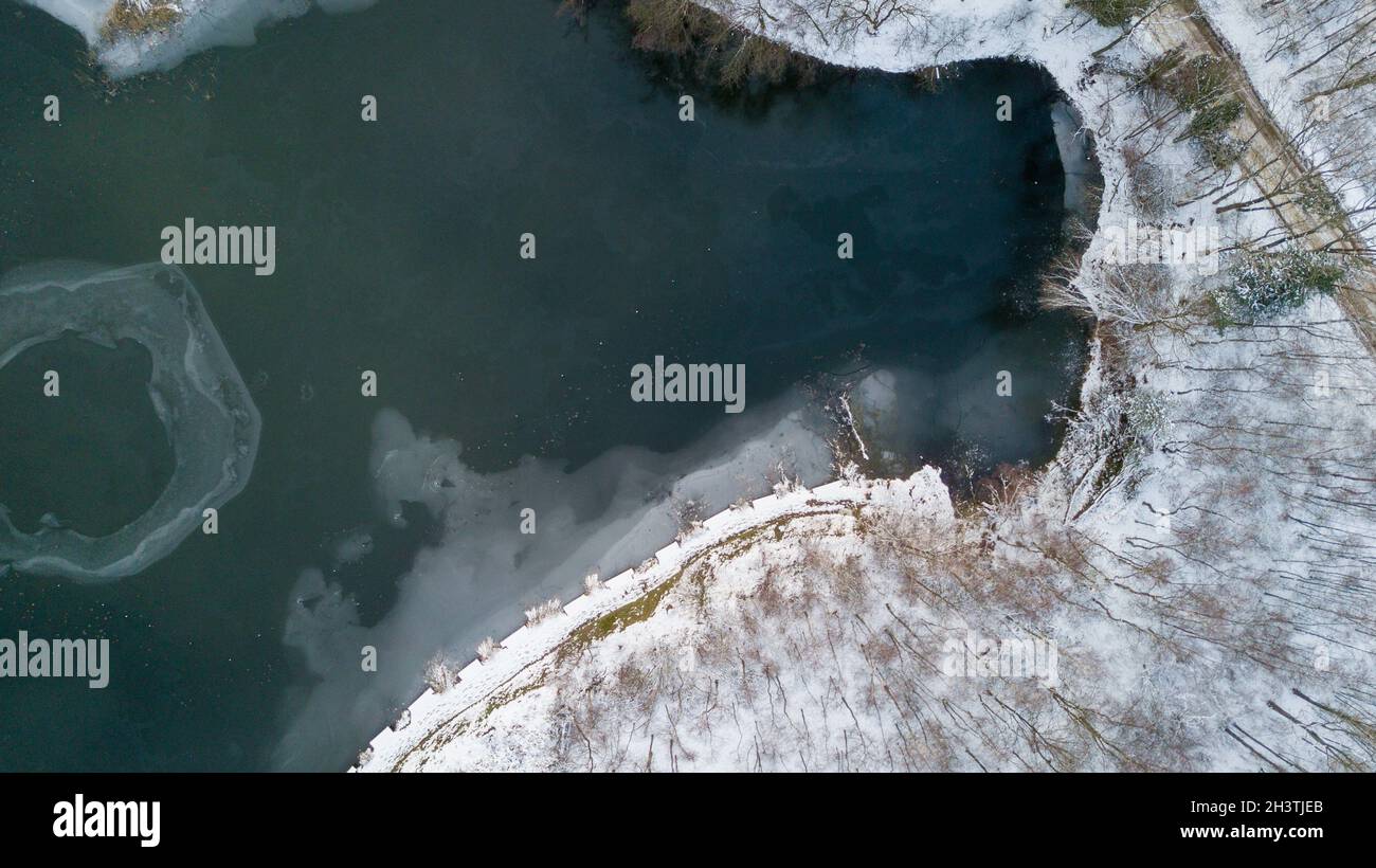 Aerial view of the winter snow covered forest and frozen lake from ...