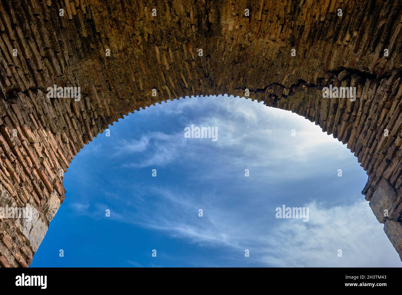 architectural arch made of red bricks wall with blue sky background in ...