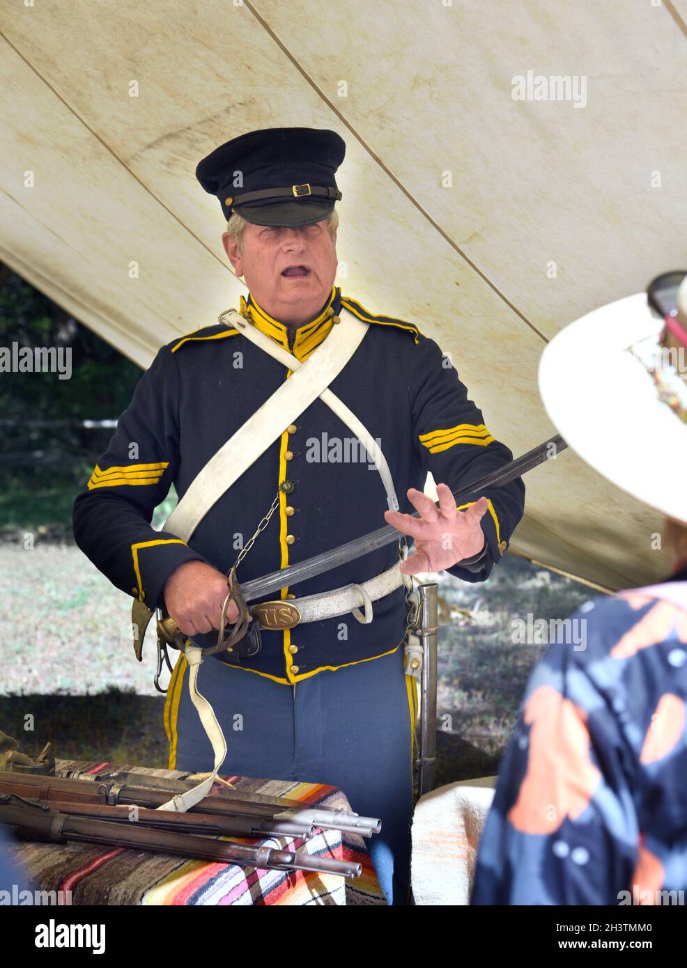 A reenactor dressed as a 19th century U.S. Dragoon soldier talks to ...