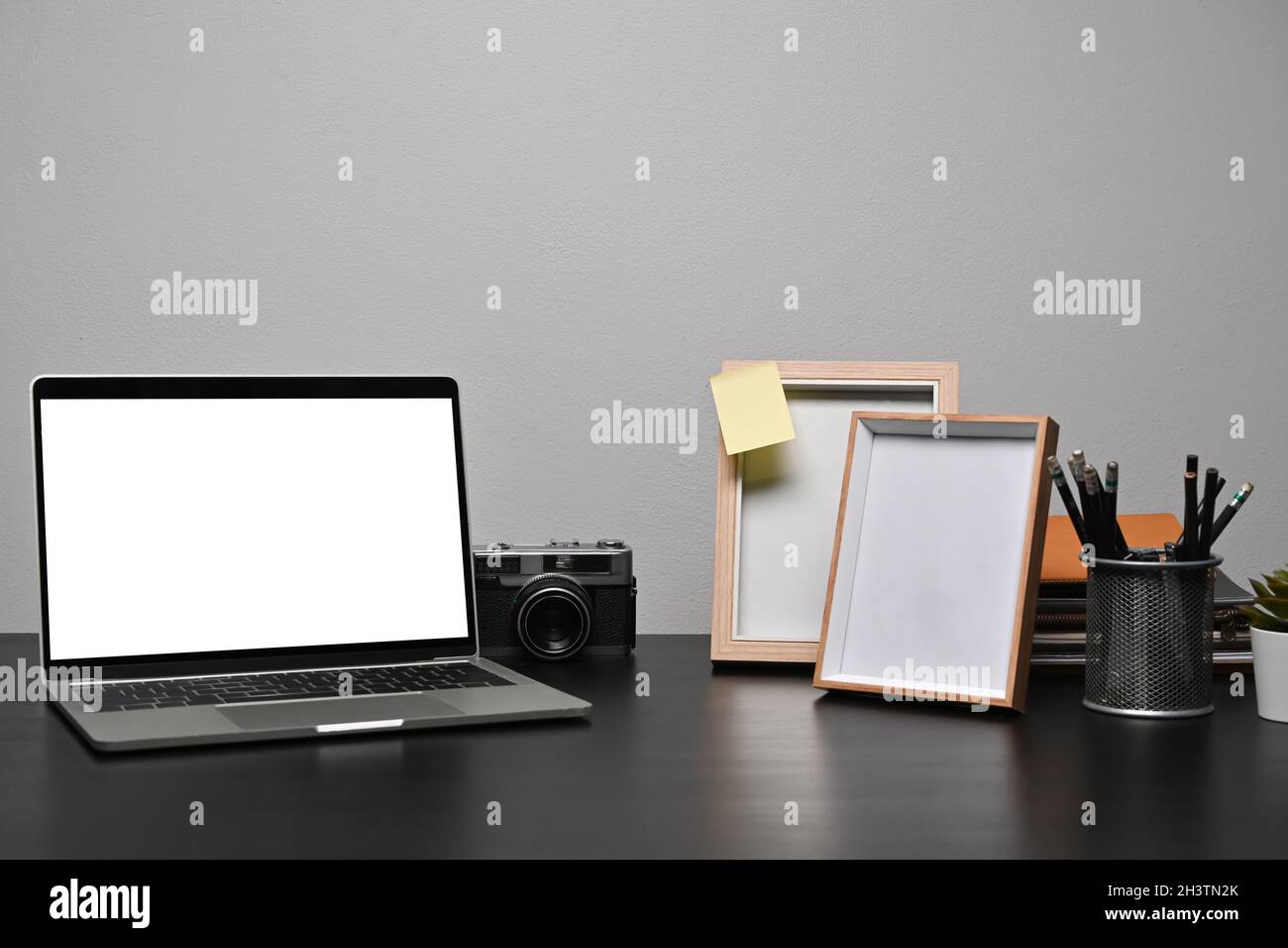 Laptop computer with white screen, camera and empty picture frames on ...
