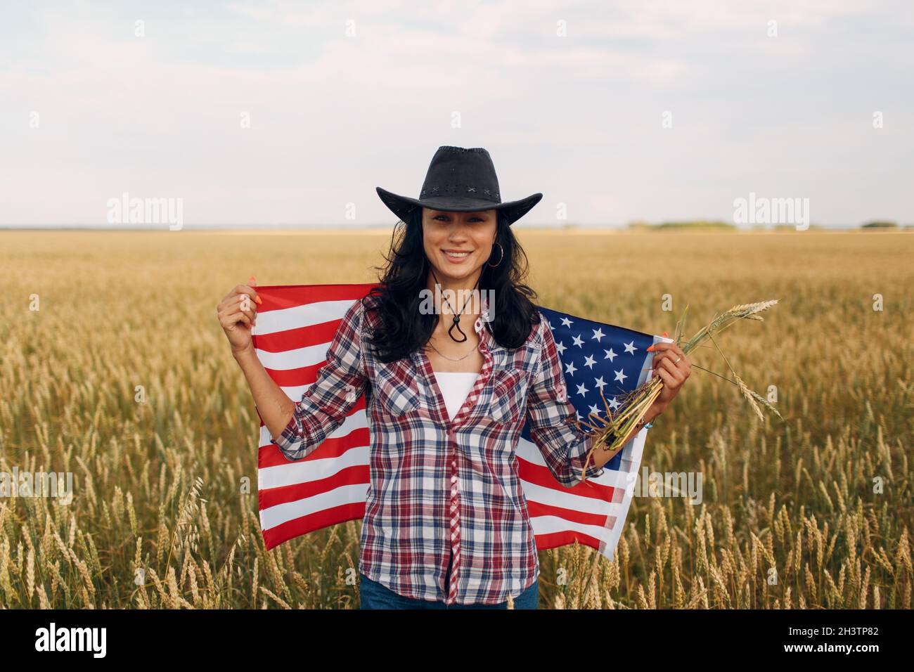 Woman farmer wearing cowboy hat, plaid shirt and jeans with american ...
