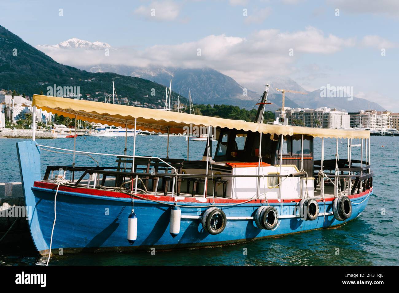 Wooden tourist boat moored against the backdrop of Porto Montenegro and ...