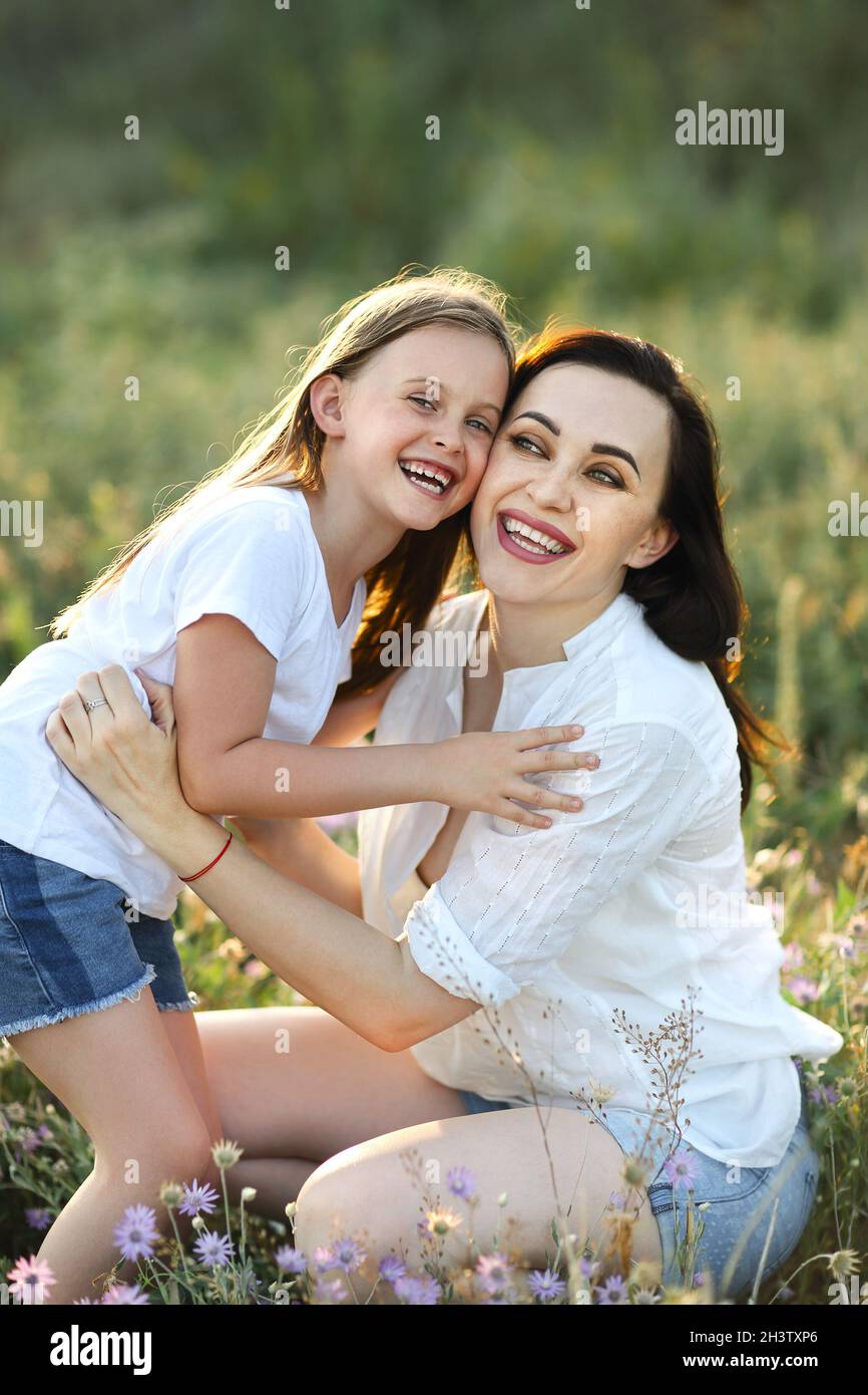Happy woman and girl hugging in field Stock Photo - Alamy