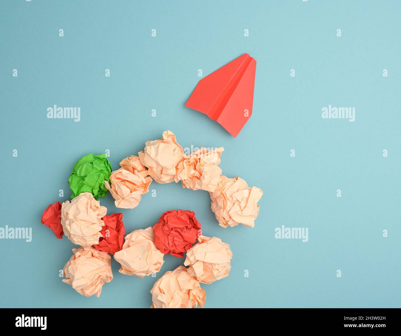 Red paper airplane and crumpled paper balls on a blue background, top ...